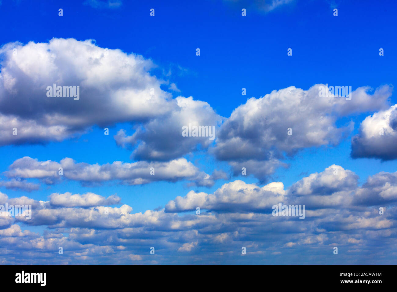 A background of blue saturated sky with the texture of white, gray and ...