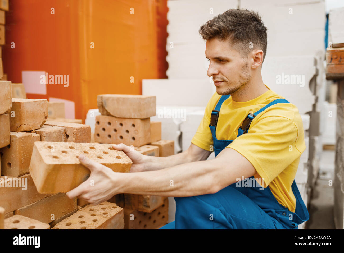 Male builder choosing bricks in hardware store Stock Photo - Alamy
