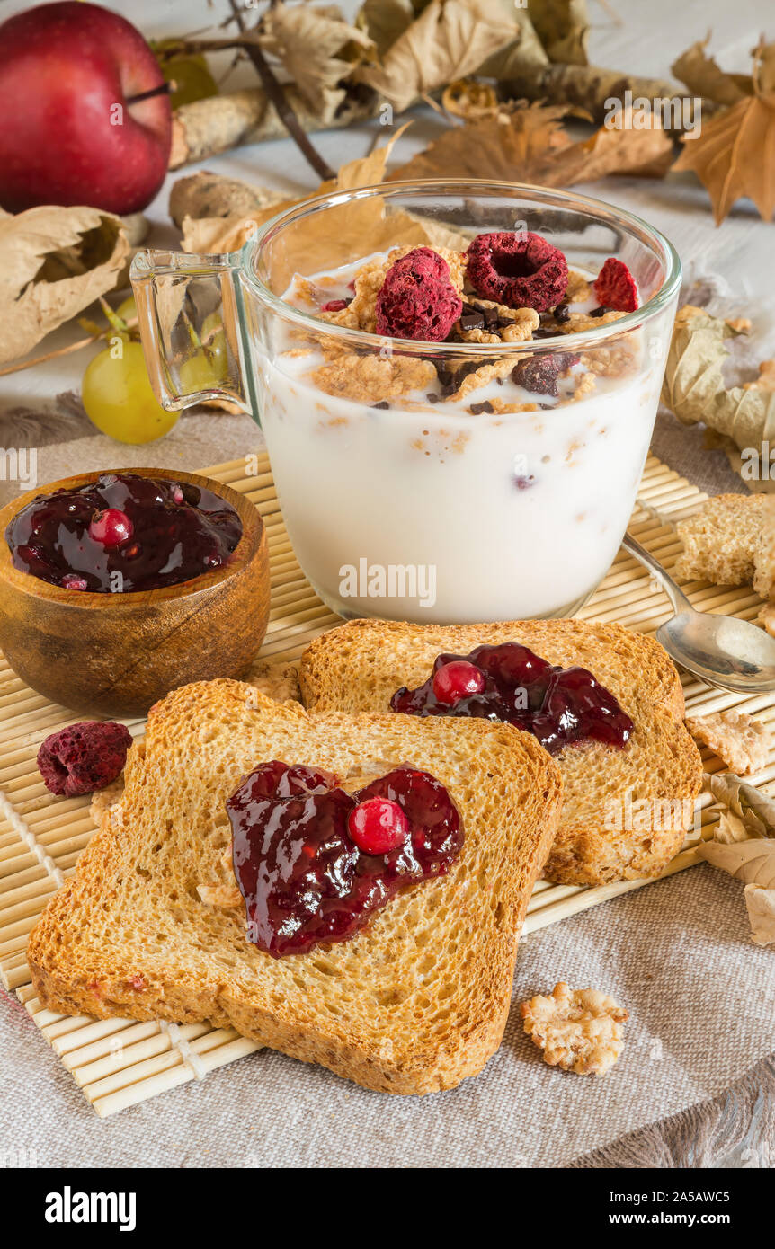 autumnal food background with milk, cereal, rusks and wildberries jam ...