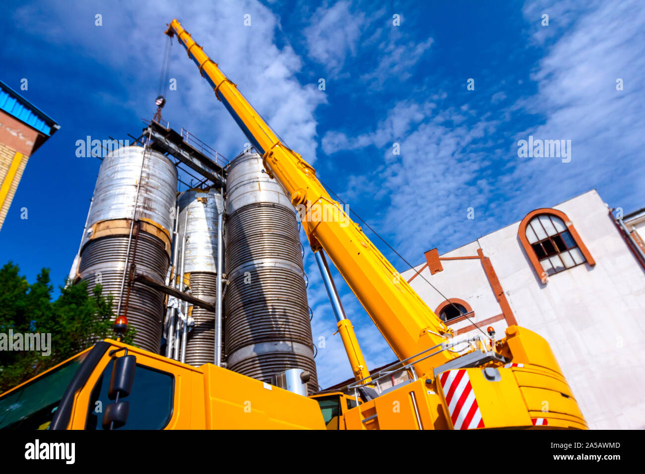 Crane is carry and keeps balance with heavy metal silo in industrial ...