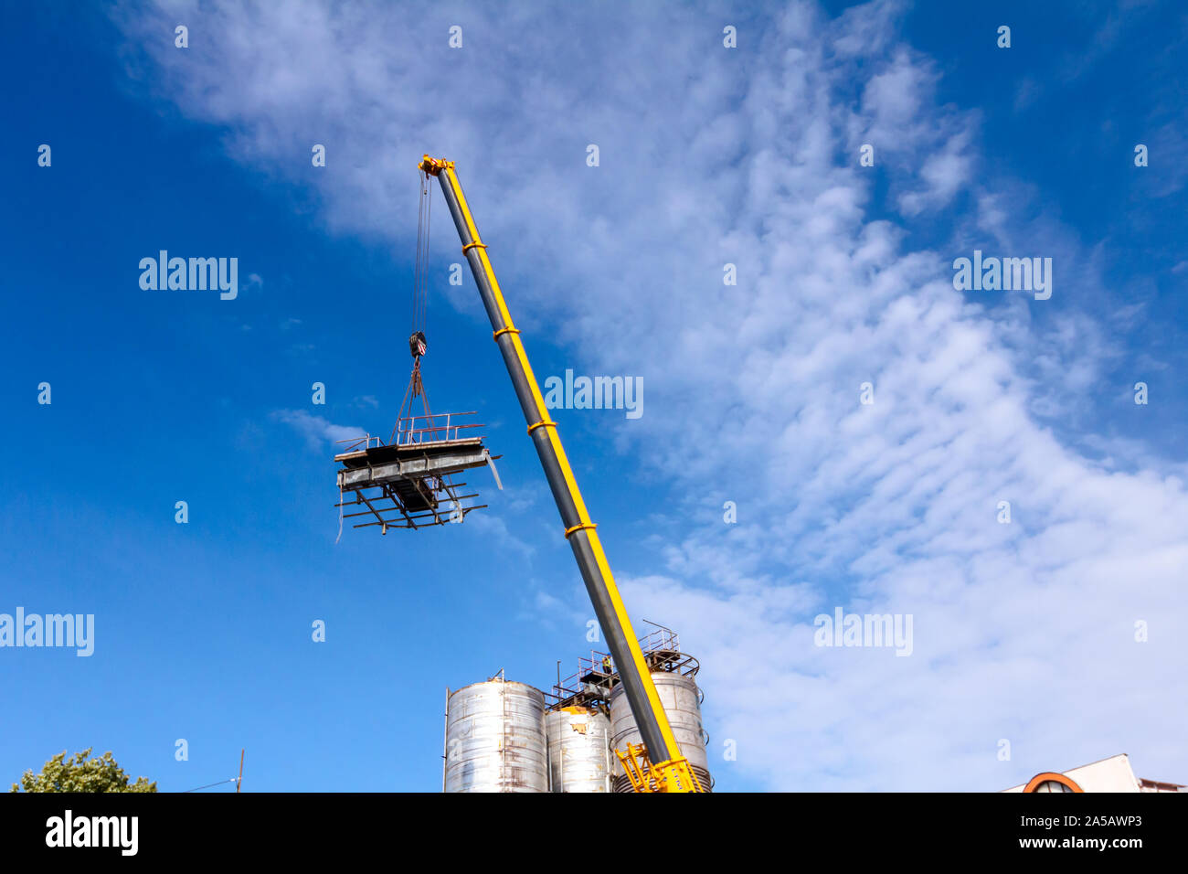 Crane is bringing down part of heavy metal construction in industrial ...