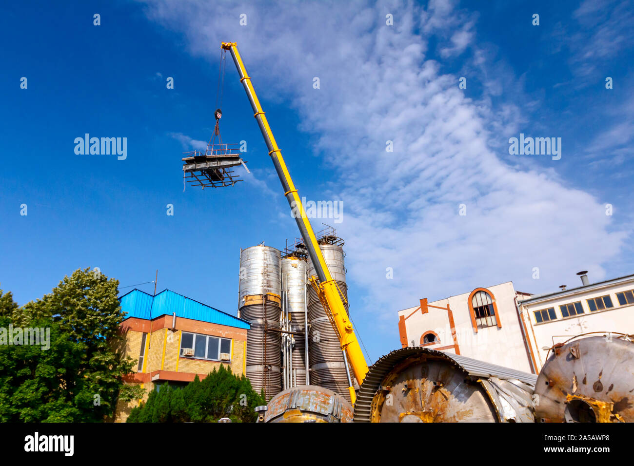 Crane is bringing down part of heavy metal construction in industrial ...