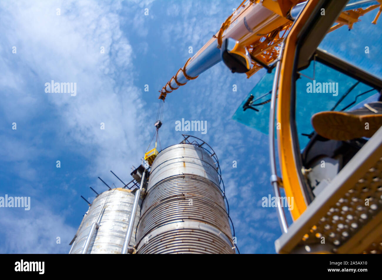 Mobile crane with hook and straps is raising work platform, basket ...