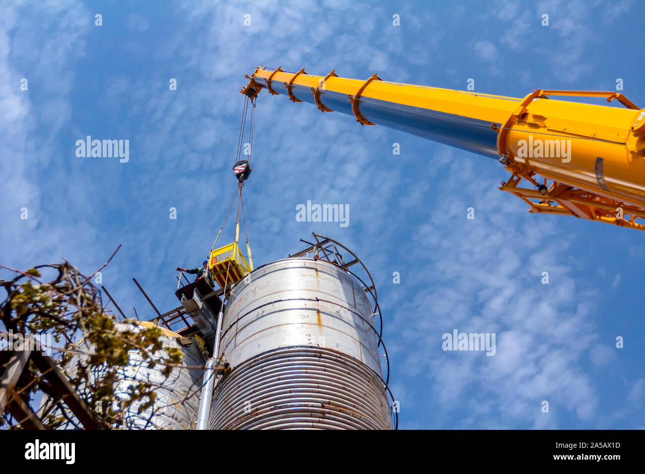 Mobile crane with hook and straps is raising work platform, basket ...