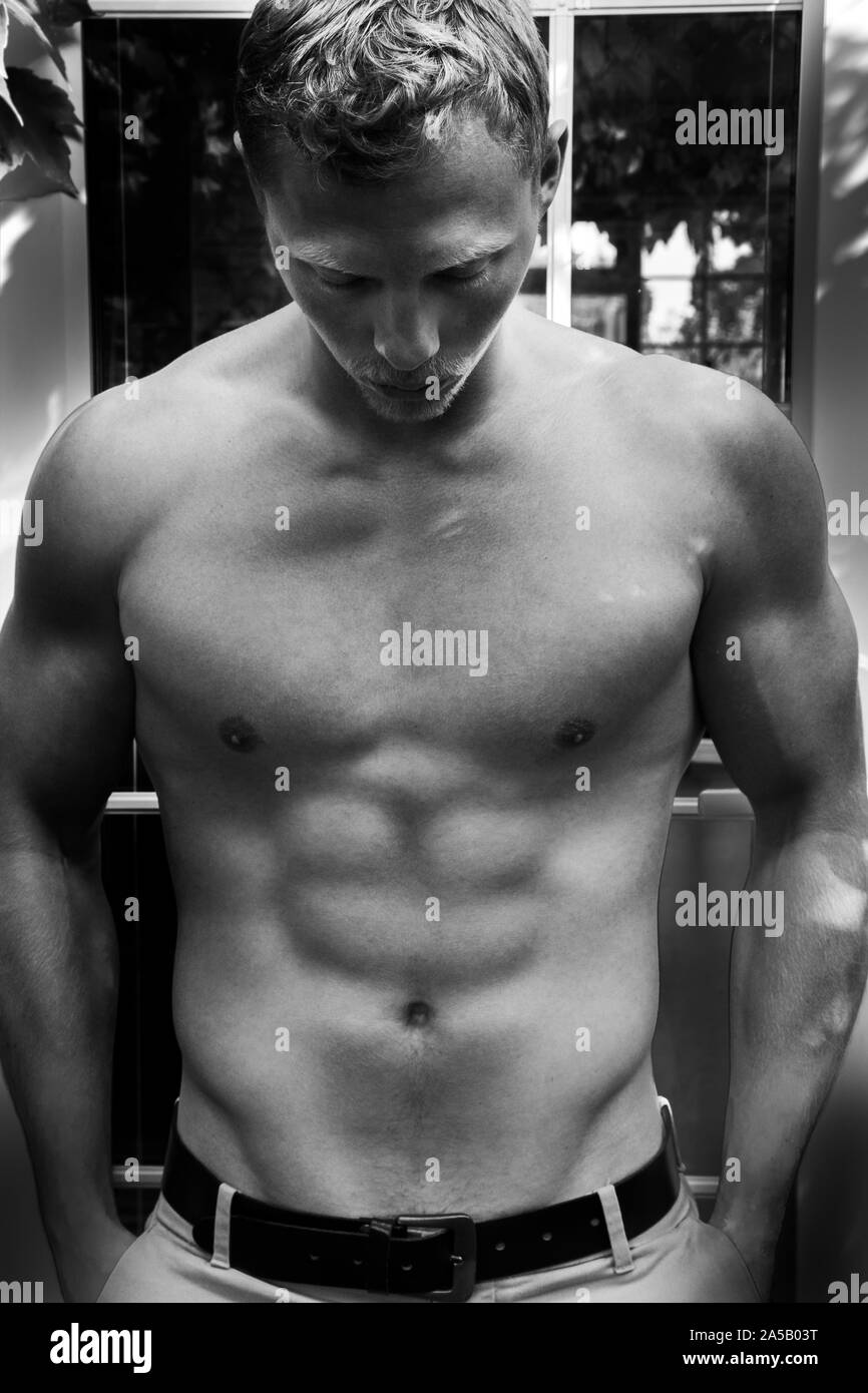 Shirtless, man with muscular pecs and abs standing in doorway with ...