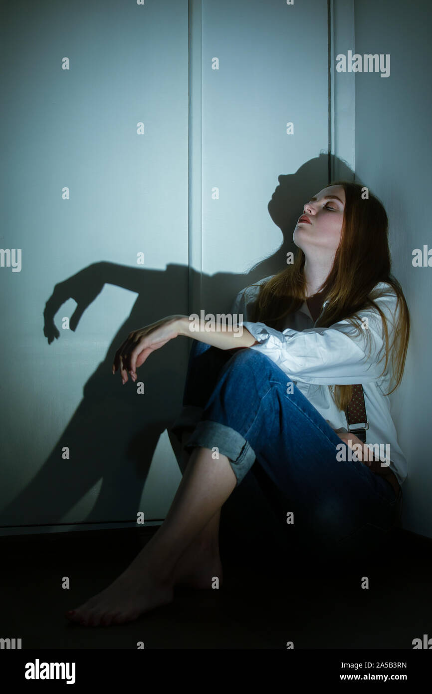 sad young woman sitting in dark in corner looking up Stock Photo - Alamy