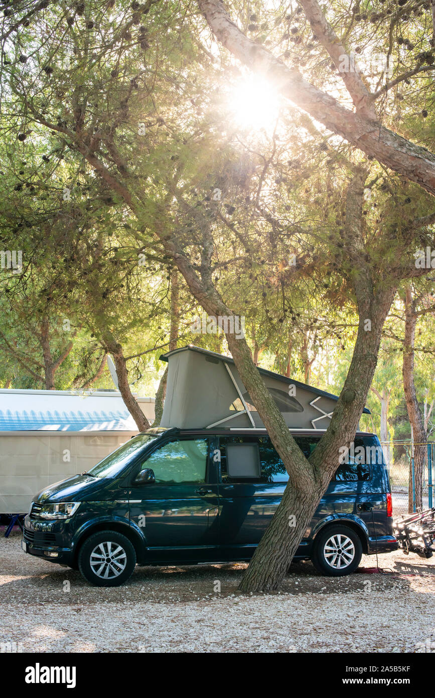 Dark blue camper caravan on camping. Morning sun. Motorhome on campsite ...
