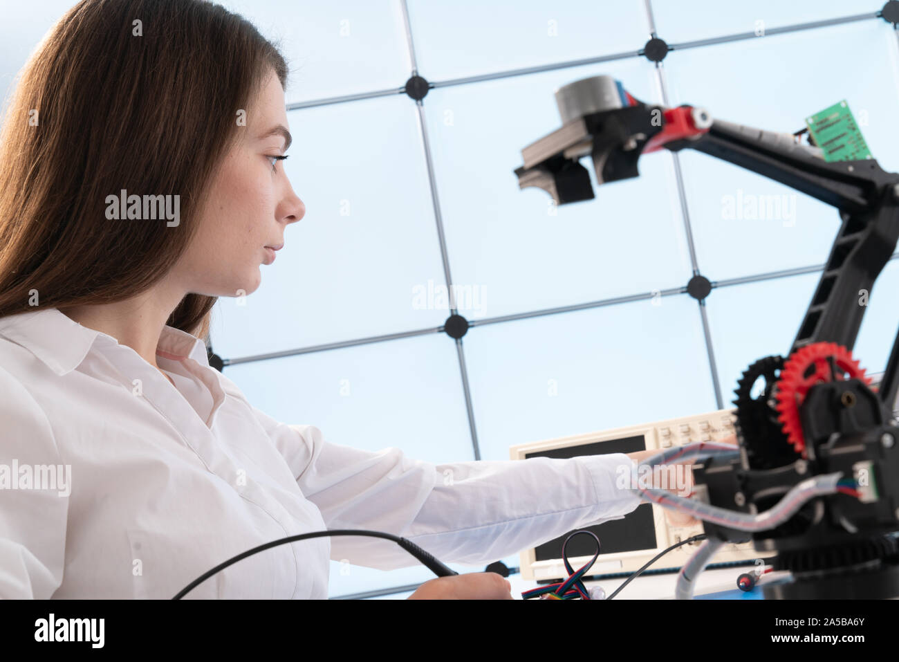 A young woman writes an algorithm for the robot arm. Science Research ...