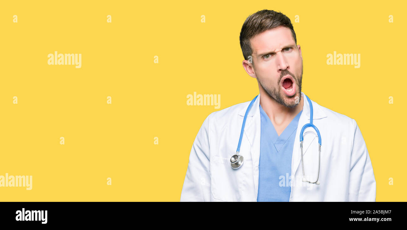 Handsome doctor man wearing medical uniform over isolated background In ...