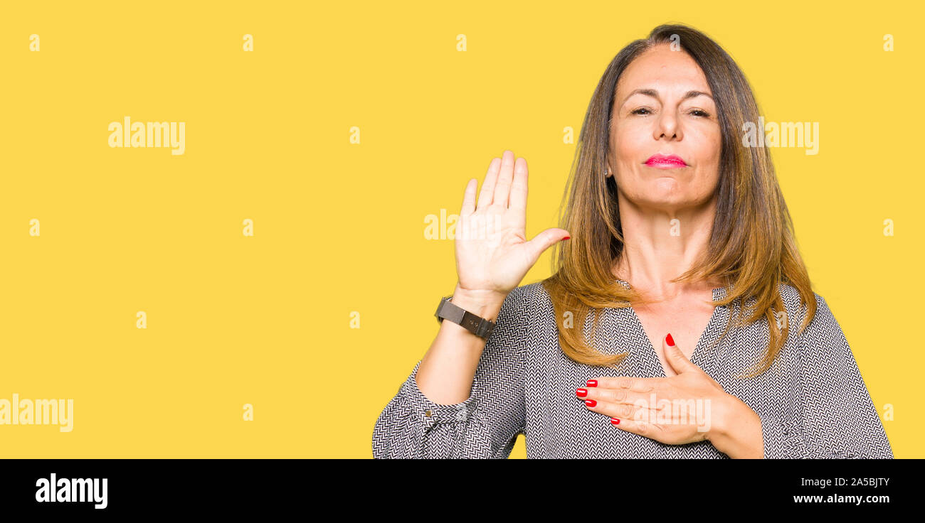 Beautiful middle age business woman Swearing with hand on chest and ...