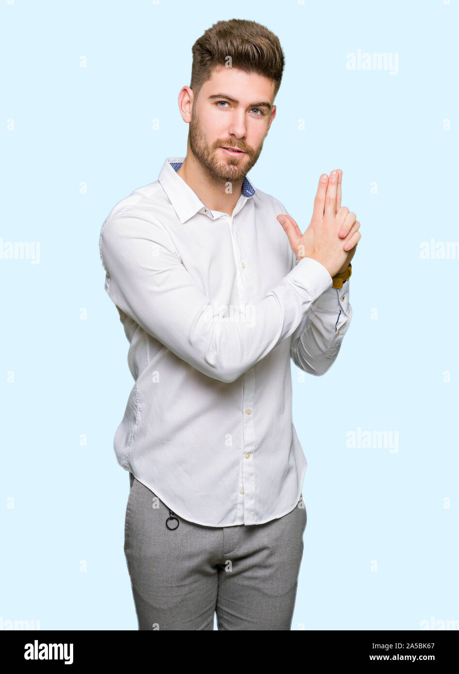 Young handsome business man Holding symbolic gun with hand gesture ...