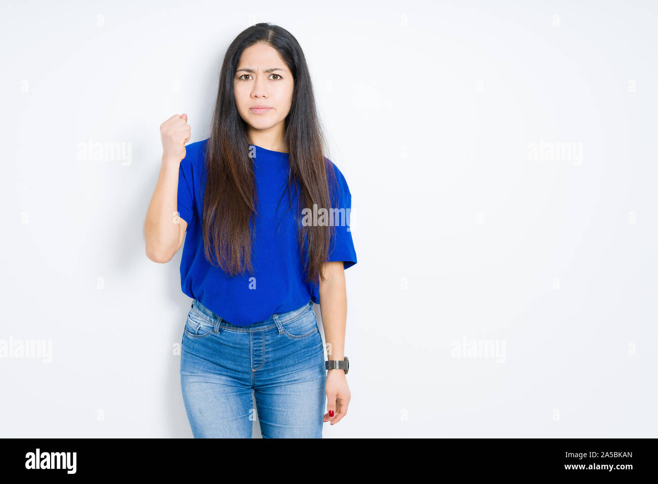 Beautiful brunette woman over isolated background angry and mad raising ...