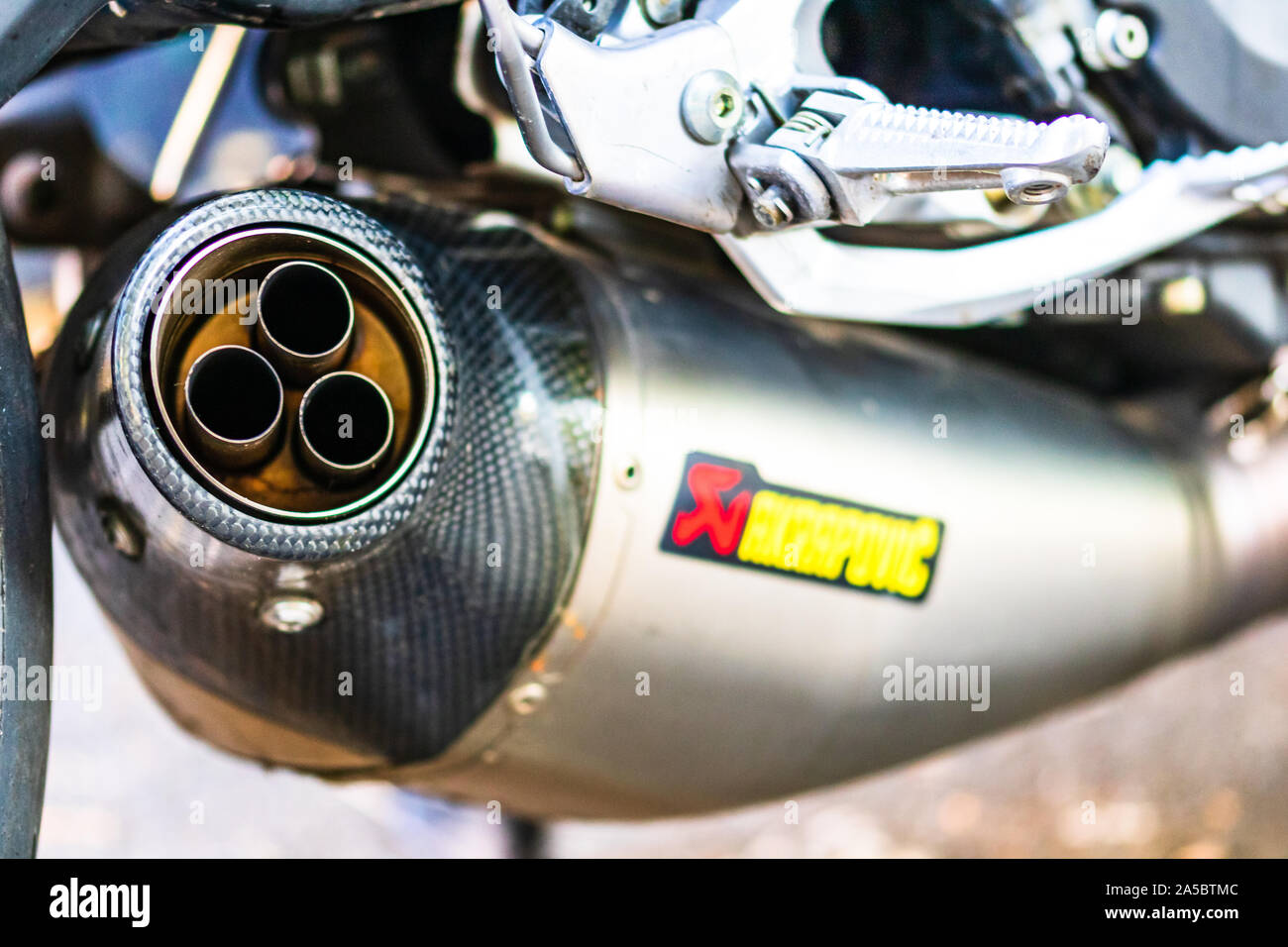 A close-up photo of Akrapovic exhaust muffler on custom motorcycle in ...