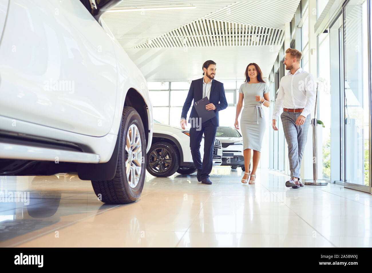Couple and the dealer selling cars look the car in the showroom Stock ...