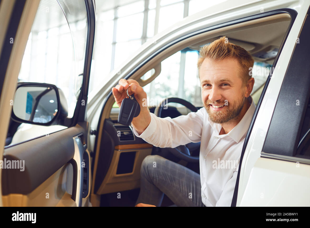 Auto buyer man with keys in hand in a new car in auto salon Stock Photo ...