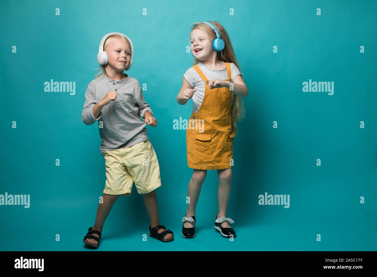 Very emotional children listen to music with headphones on a blue ...