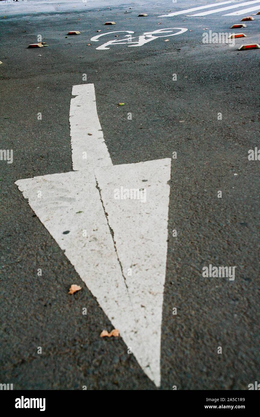 Vertical high angle shot of a white arrow sign on an asphalt road ...