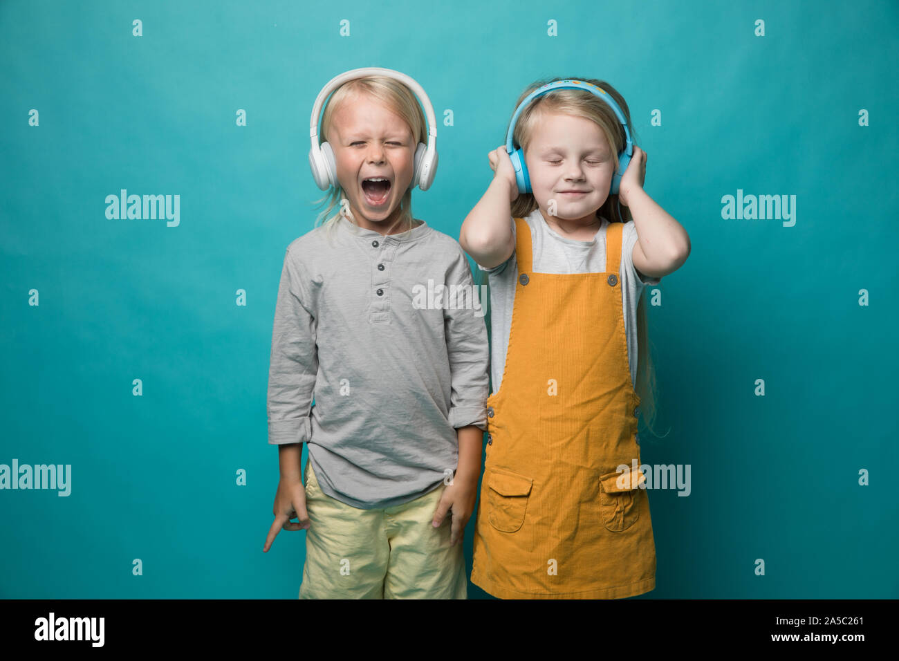 Very emotional children listen to music with headphones on a blue ...