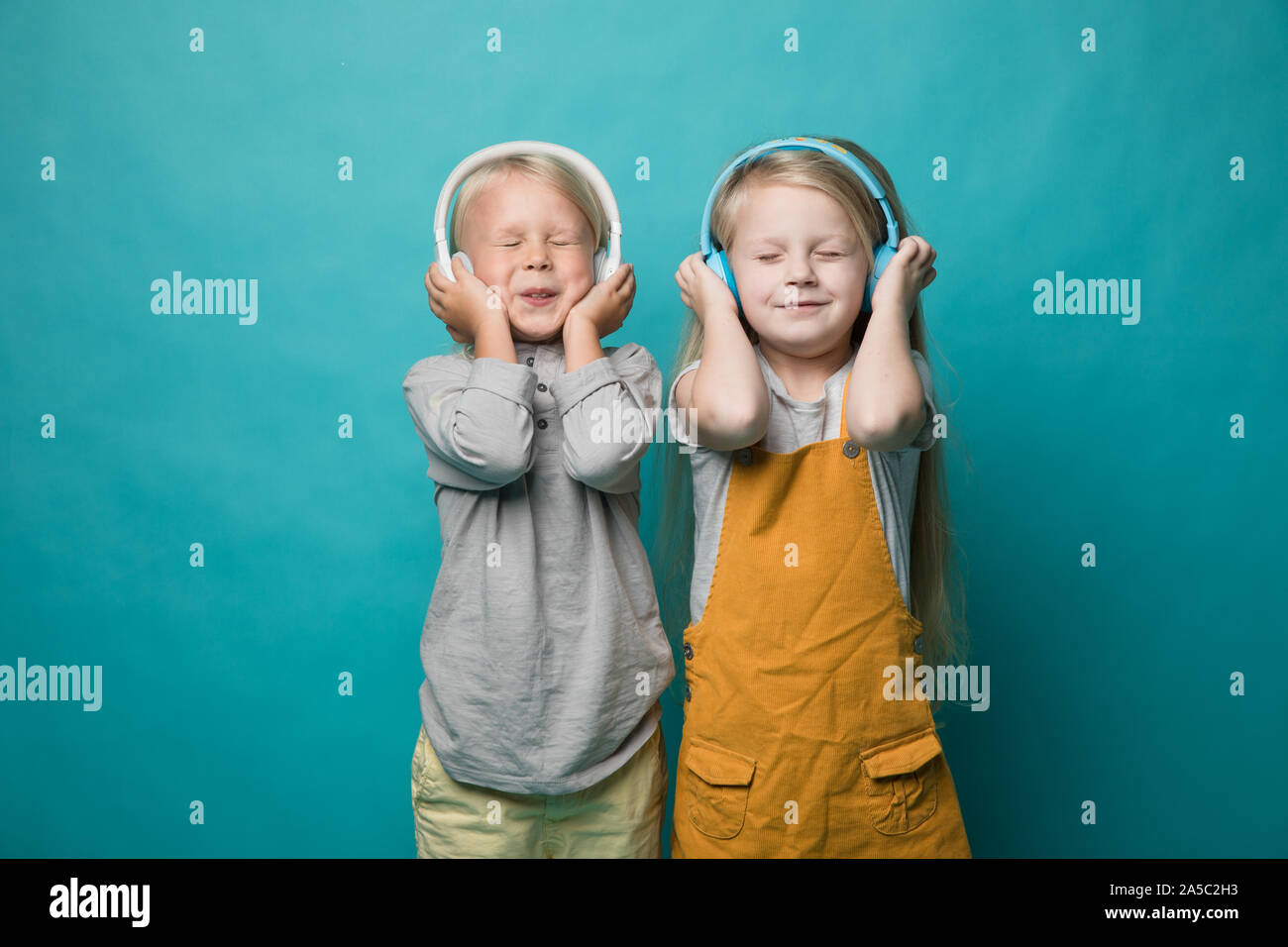 Very emotional children listen to music with headphones on a blue ...