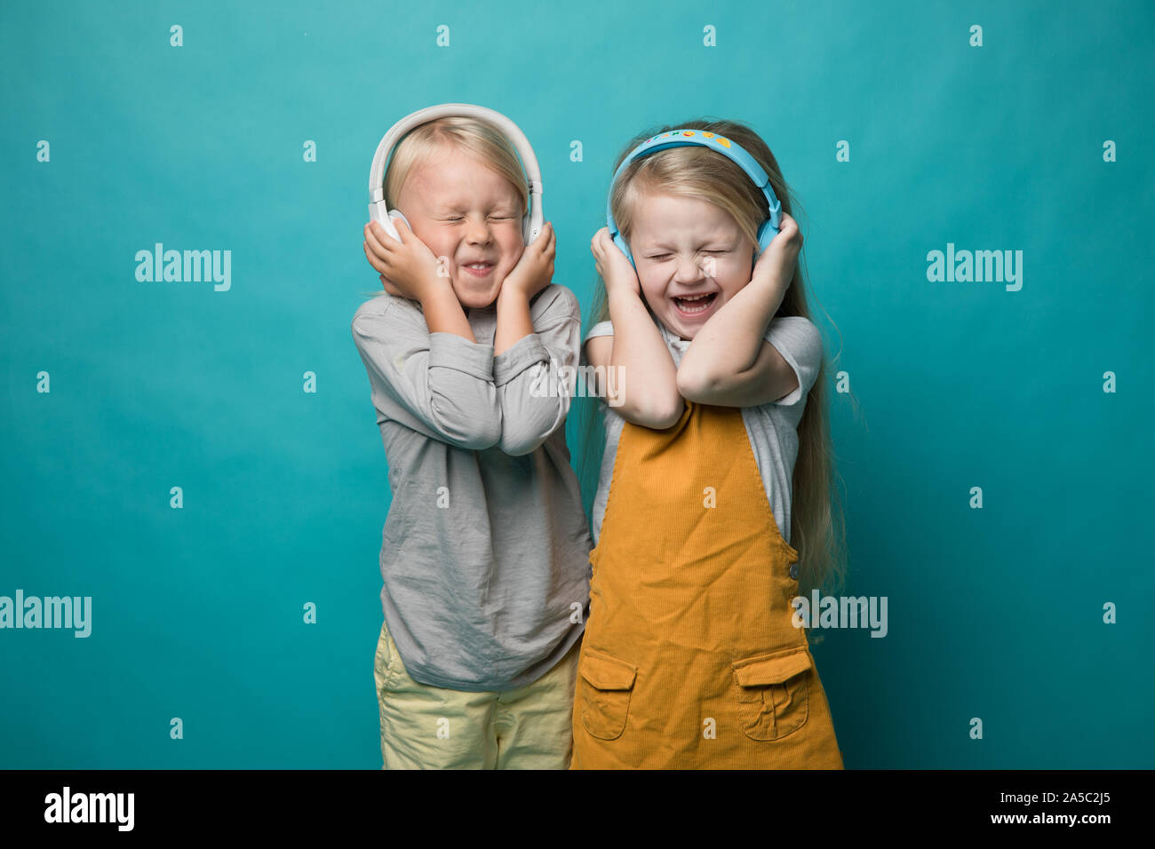 Very emotional children listen to music with headphones on a blue ...