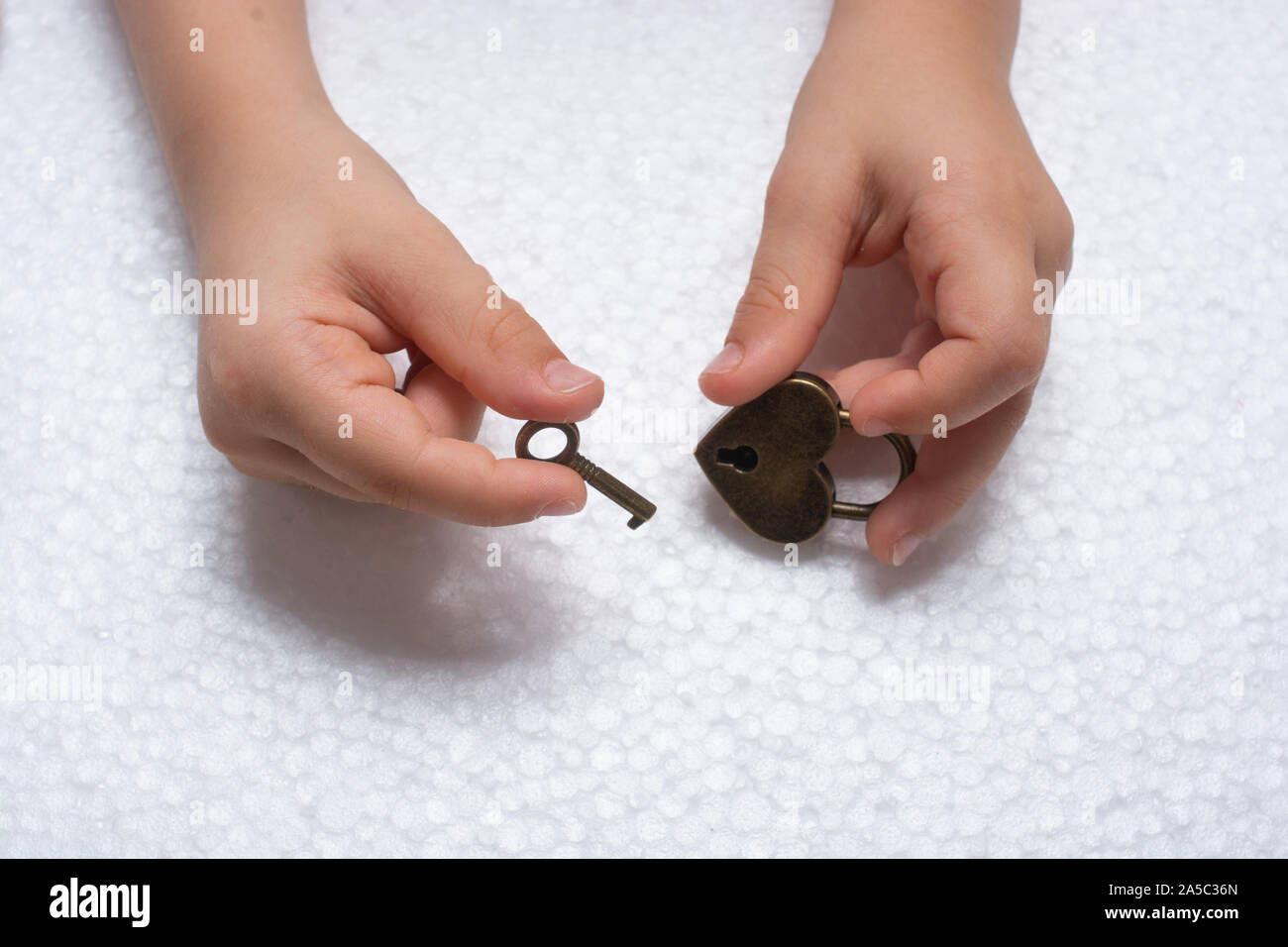 Hand holding a heart shaped lock and key on a white background Stock ...