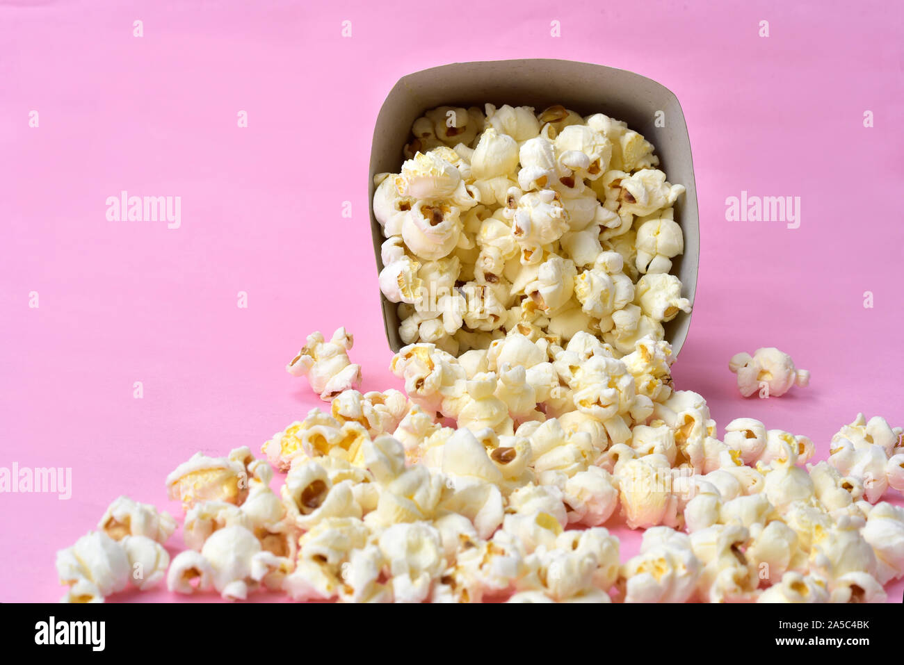 popcorn falling from paper packaging with pink background Stock Photo ...