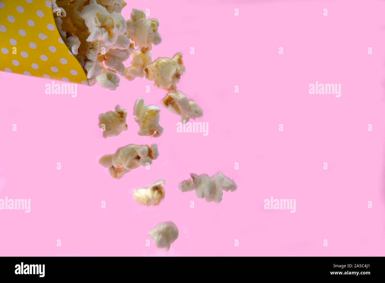 popcorn falling from paper packaging with pink background Stock Photo ...