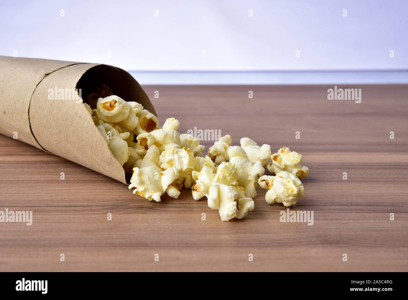 popcorn falling from paper packaging with wood background Stock Photo ...
