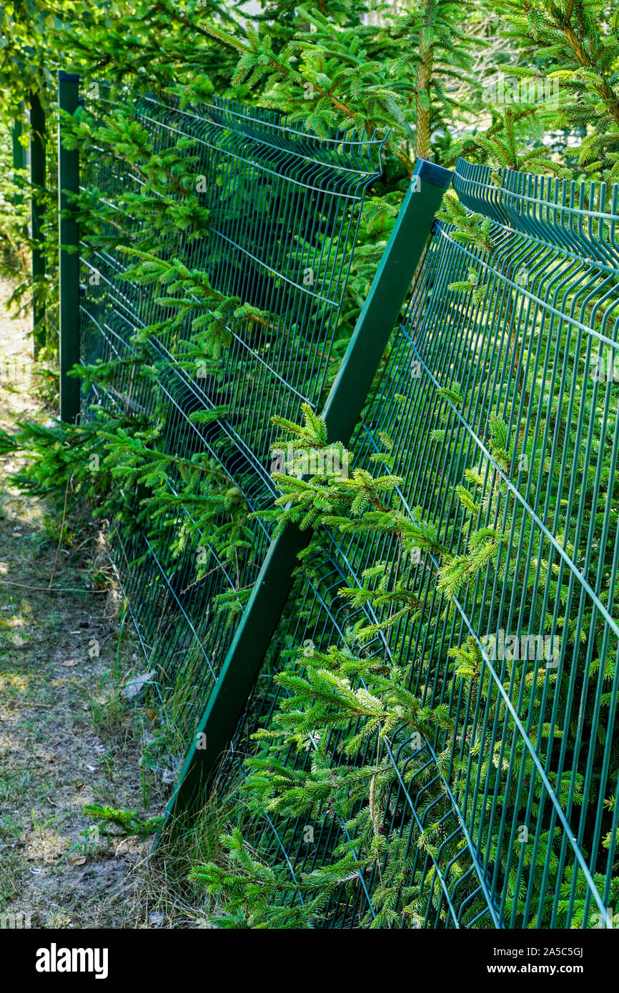 a fragment of a broken metal fence and a deformed fence post Stock ...