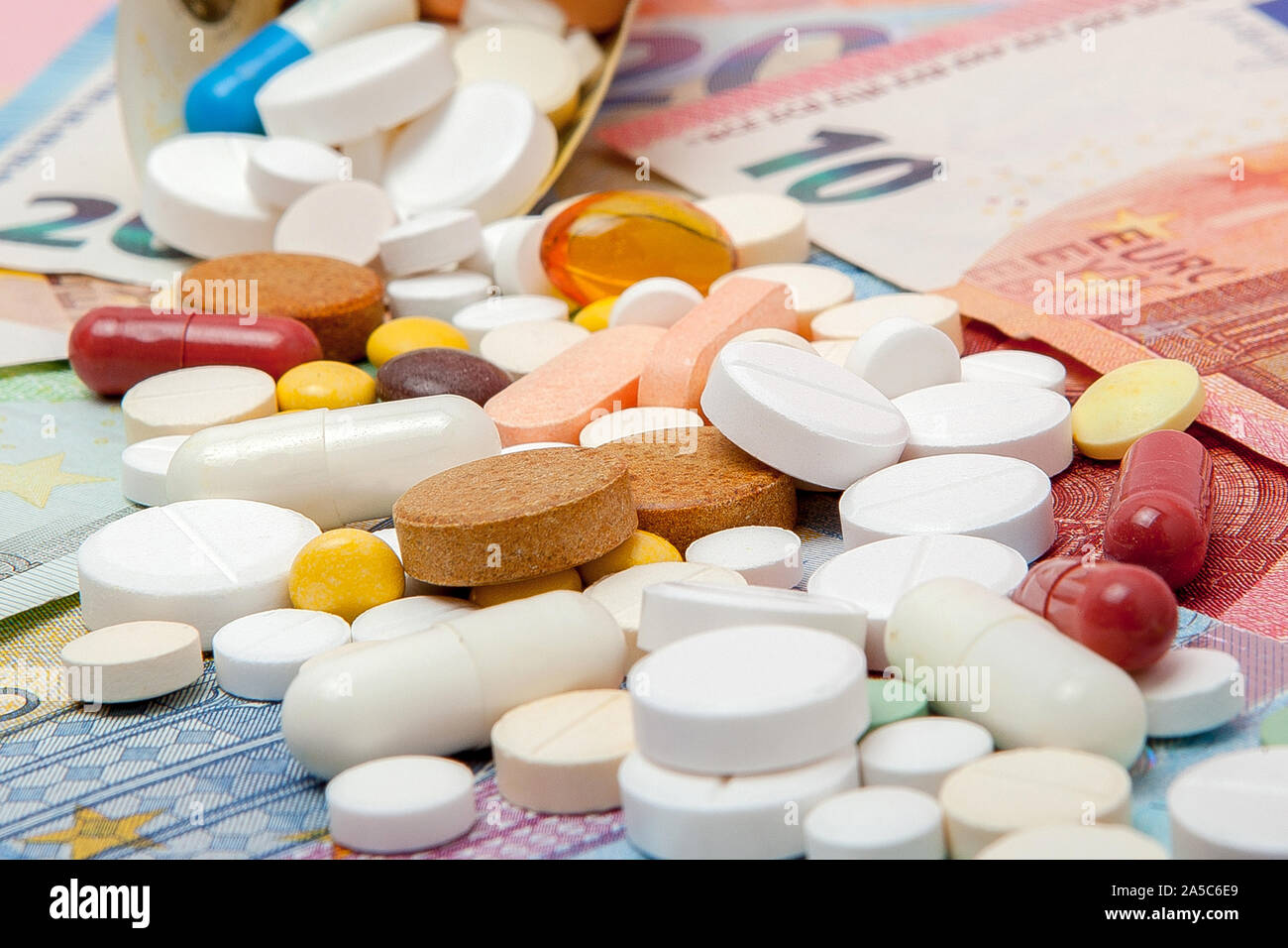 The tablets wrapped in euro with euro banknotes on a pink background ...