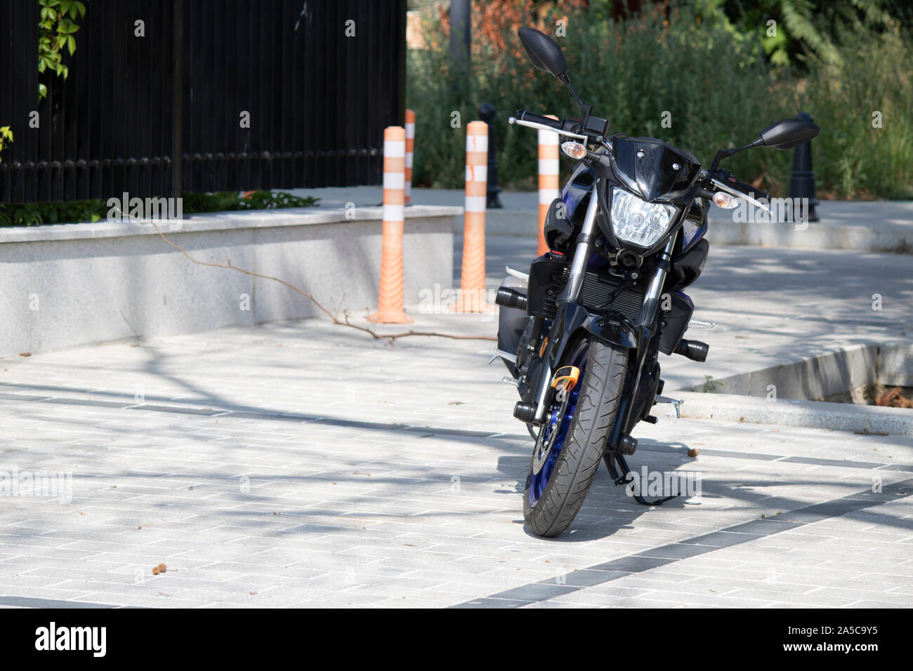 Black motorcycle parked on the curb. Pulled ahead. There are iron ...