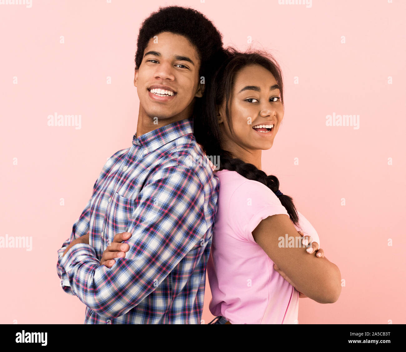 Joyful couple standing back to back with crossed hands Stock Photo - Alamy