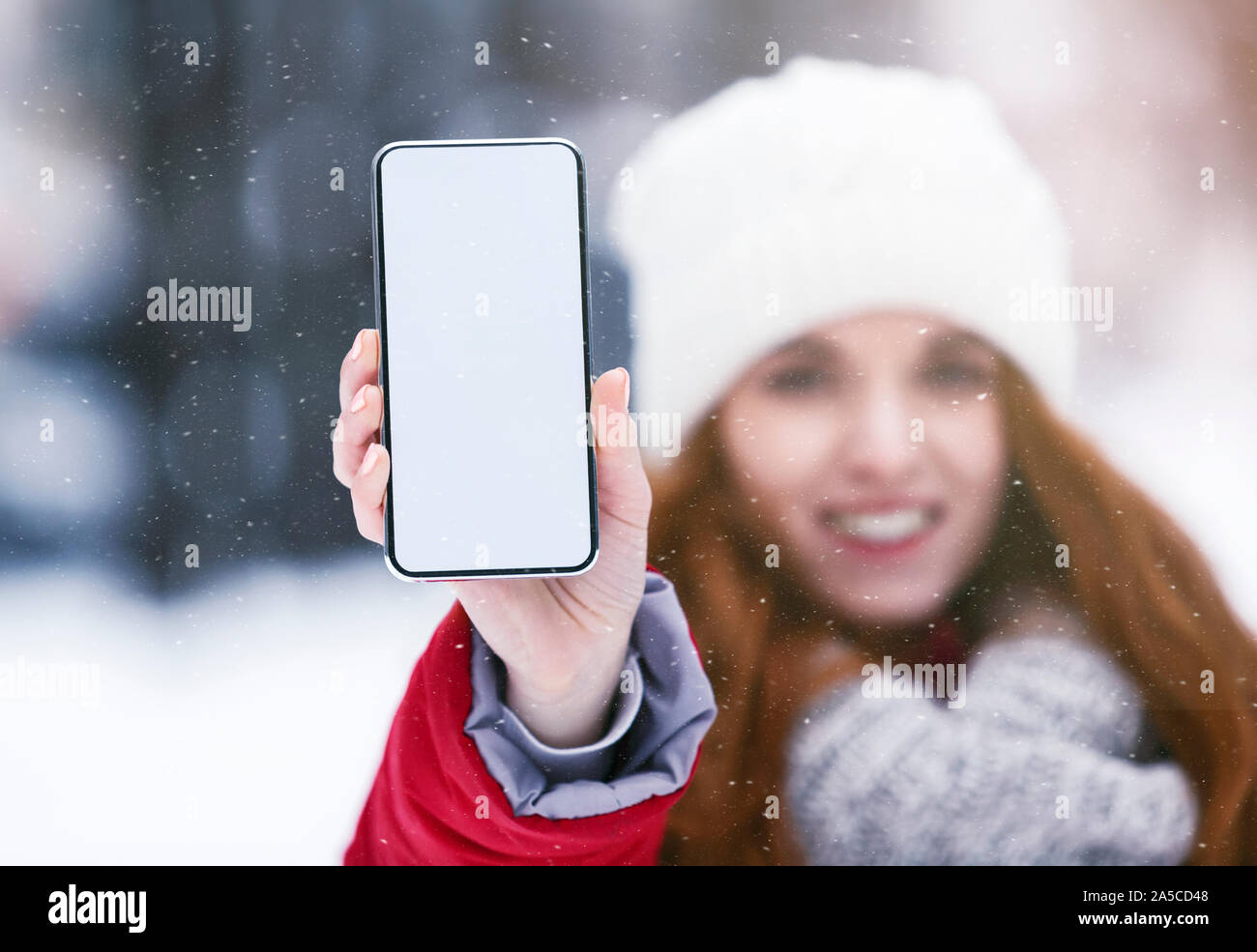 Girl showing blank smartphone screen in snowy park Stock Photo - Alamy