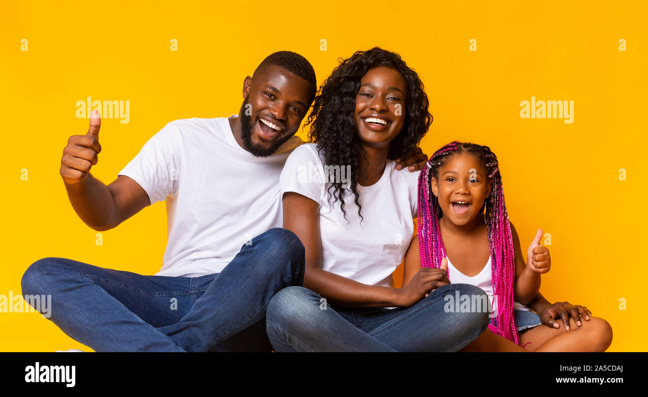 Happy parents and their daughter showing thumbs up, recommending ...