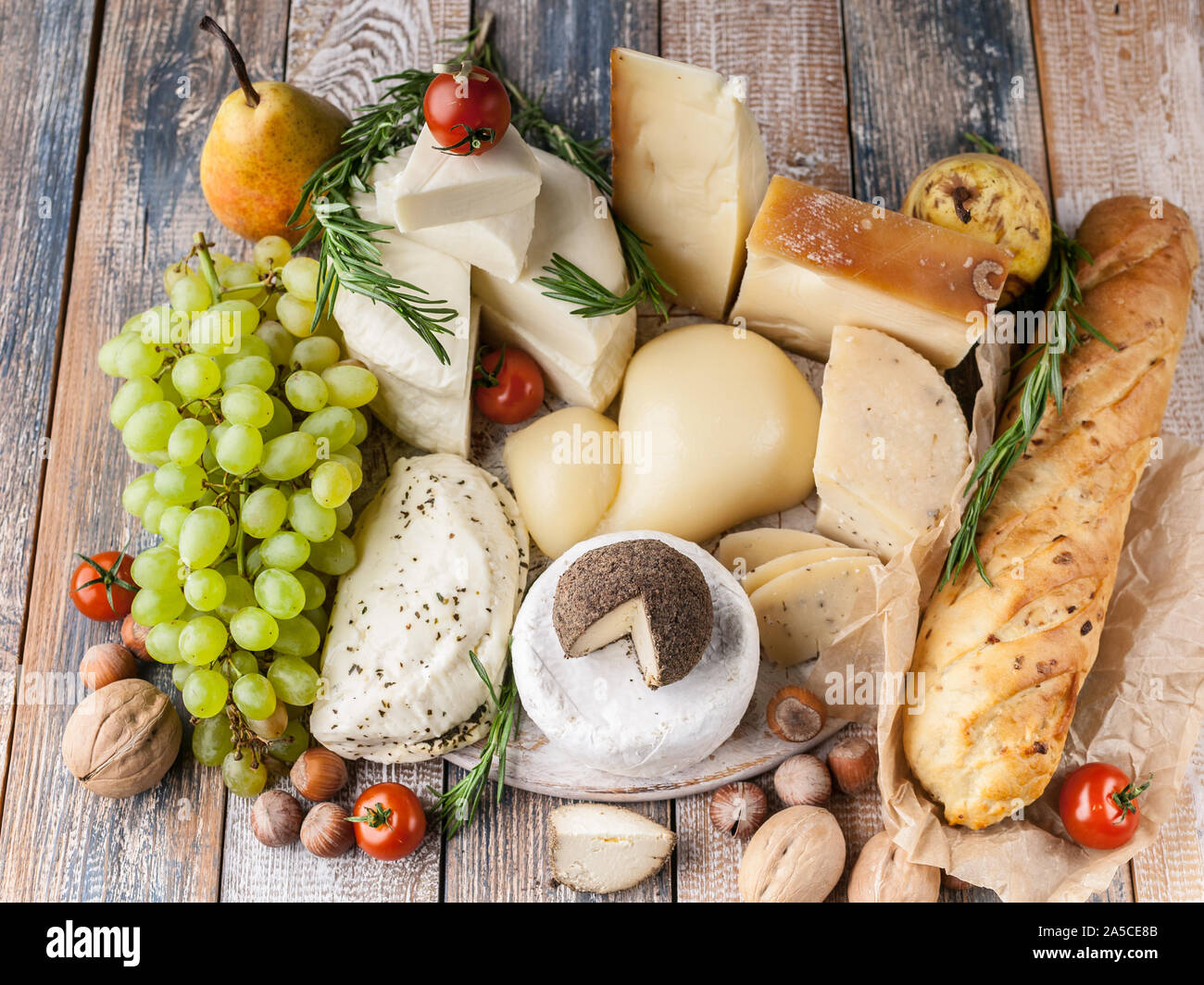 Different types delicious cheeses, nuts, fruits, spicy herbs and onion ...