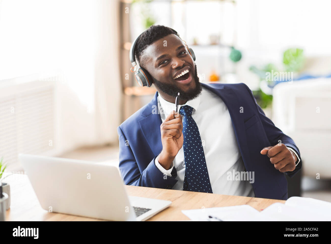 Young positive black manager singing at workplace Stock Photo - Alamy