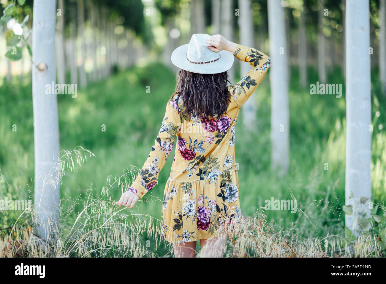 Young woman, wearing flowered dress, between trees Stock Photo - Alamy