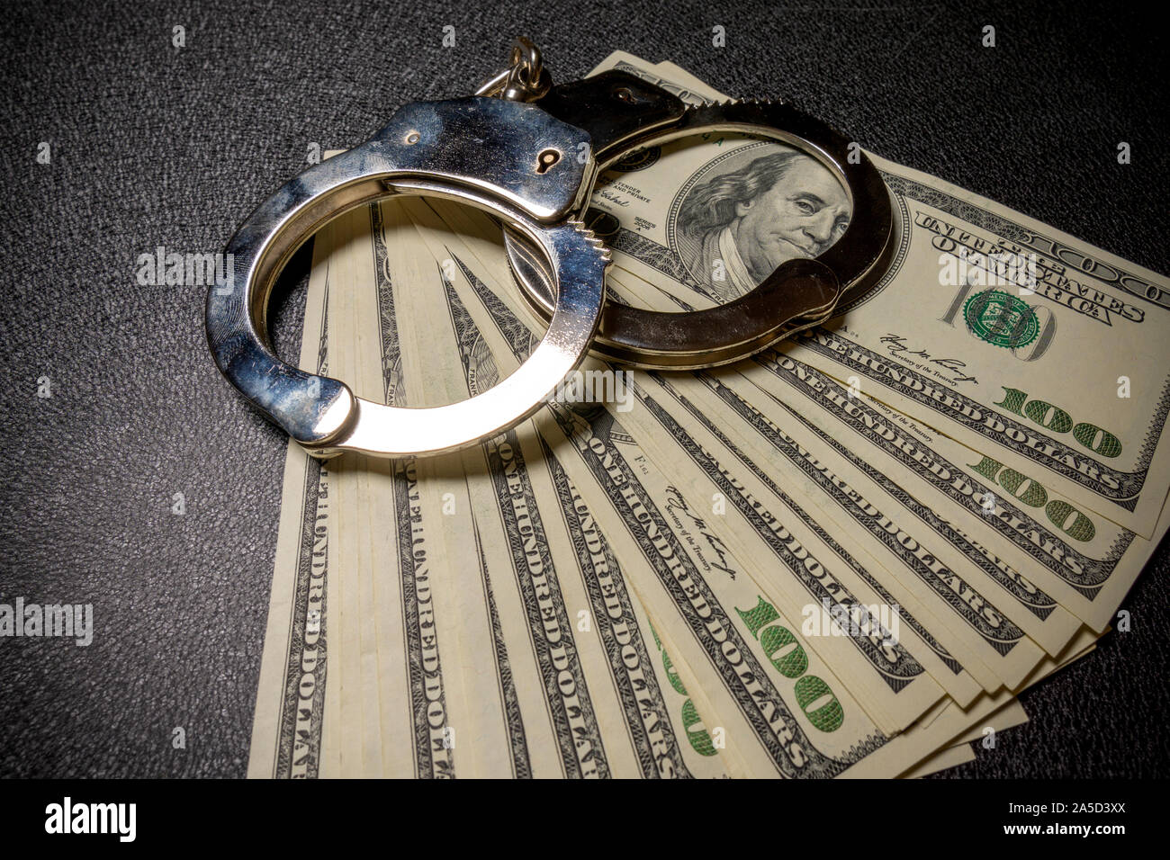 Handcuffs on hundred dollar american banknotes on black background. The ...