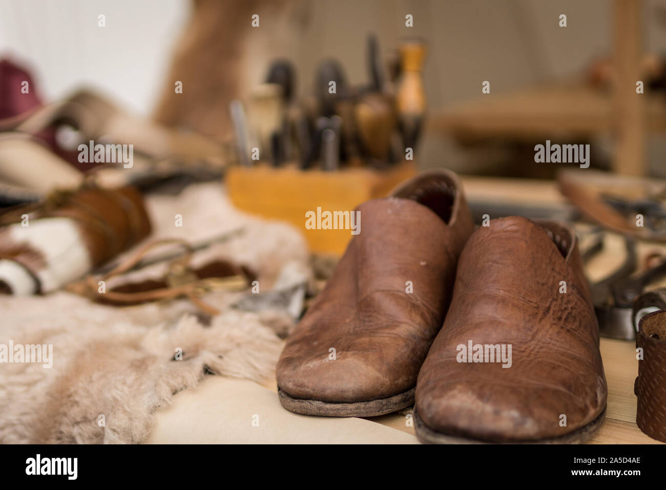 Shoemaker working desk with focus on ready shoes foreground and set of ...