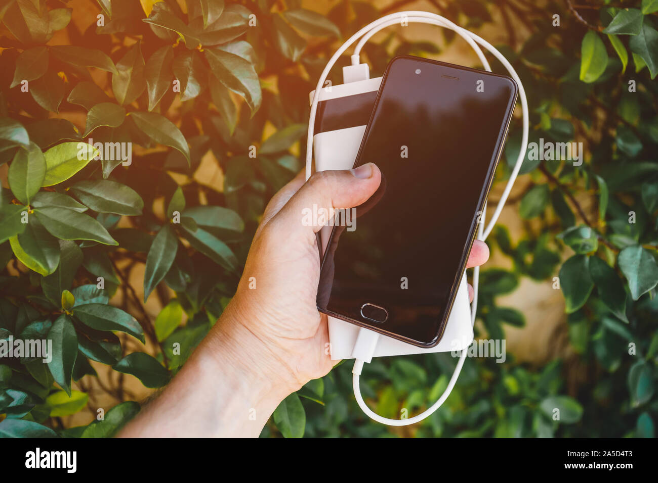Male hand holding mobile phone with external charging battery power ...
