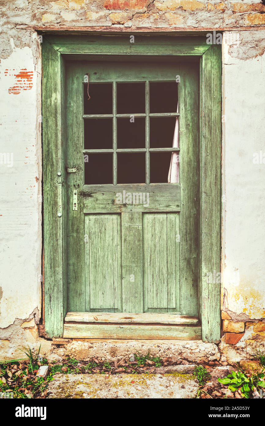 An old rotten wooden door on crumbling house. Vintage matte look effect ...