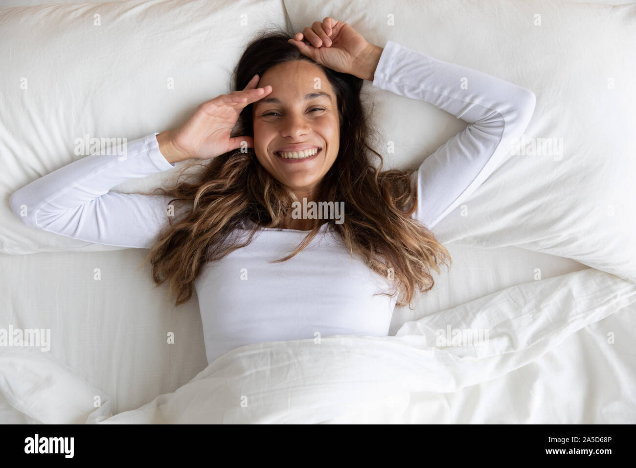 Sincere smiling young mixed race woman waking up in morning Stock Photo ...