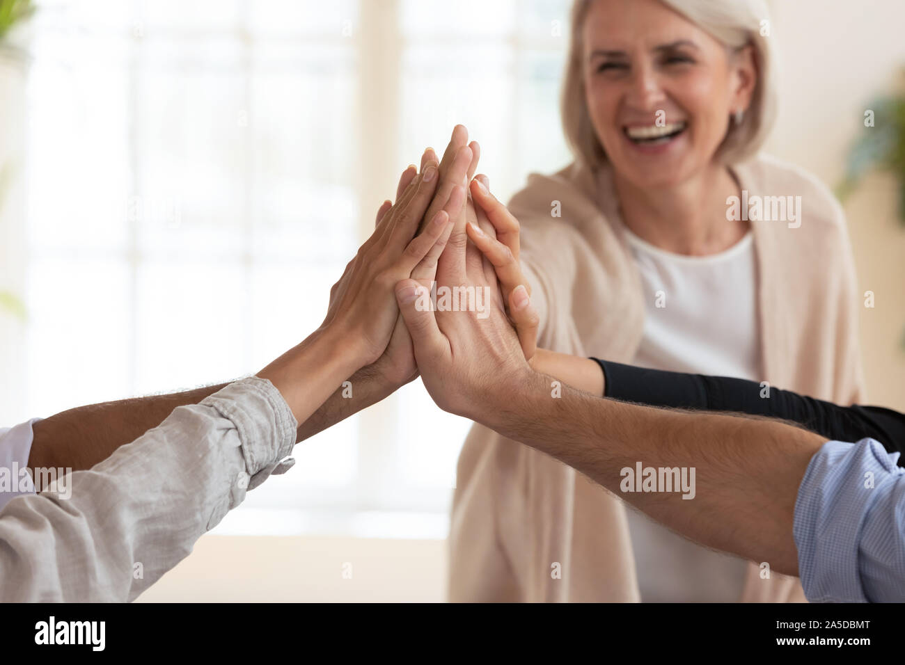Happy corporate team with senior mentor give high five, closeup Stock ...