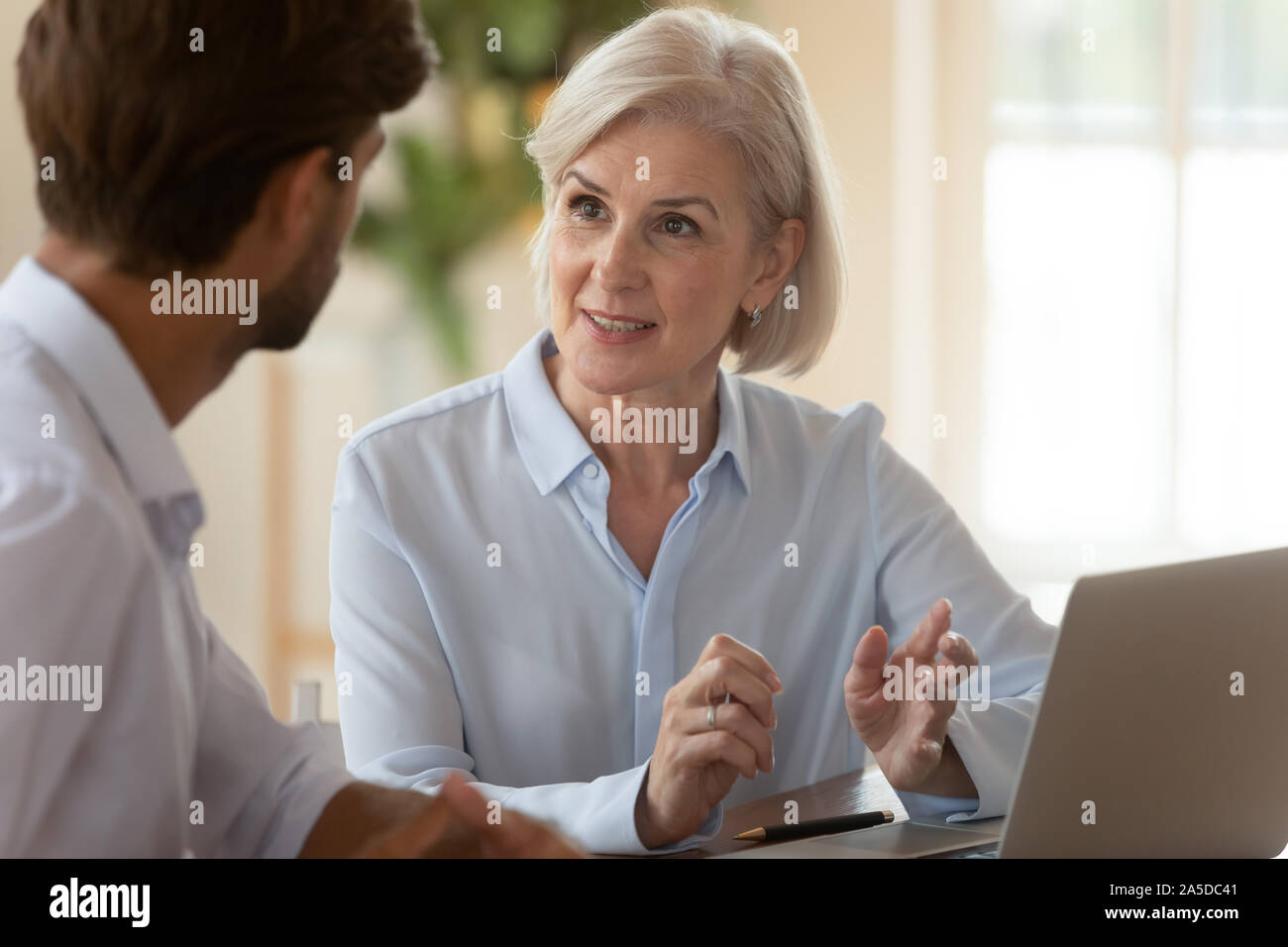 Middle aged businesswoman manager speaking to businessman client ...