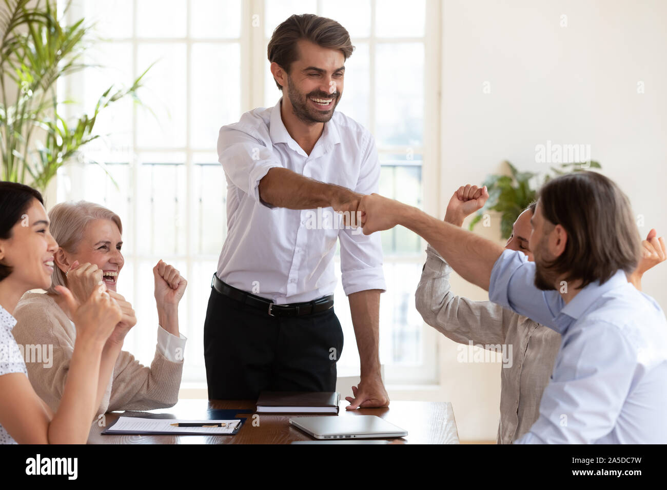 Excited businessmen fist bumping at meeting celebrating corporate ...