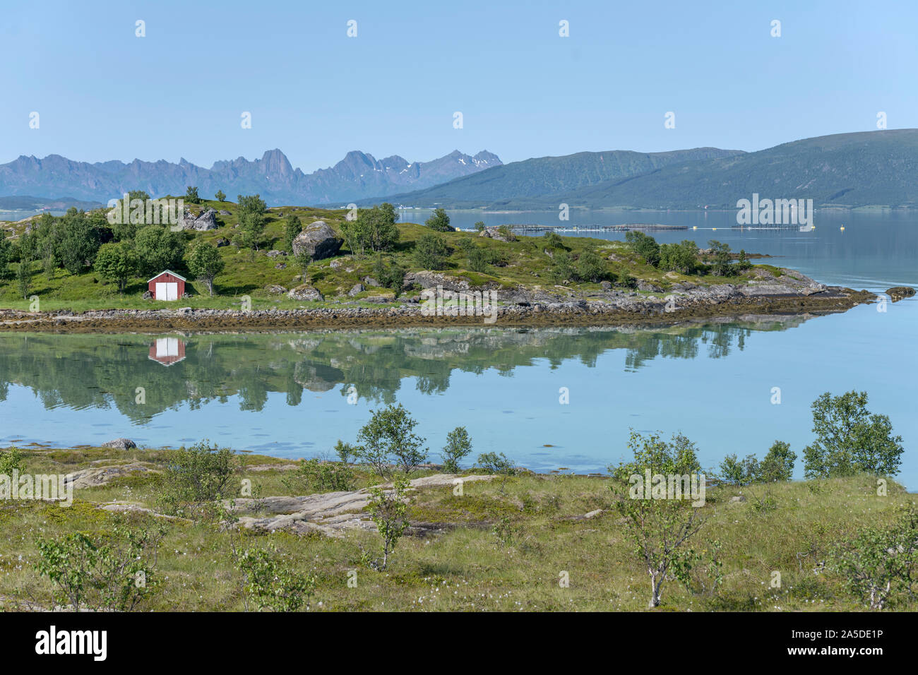 landscape with small hut at fjord inlet and fish farm, shot under ...