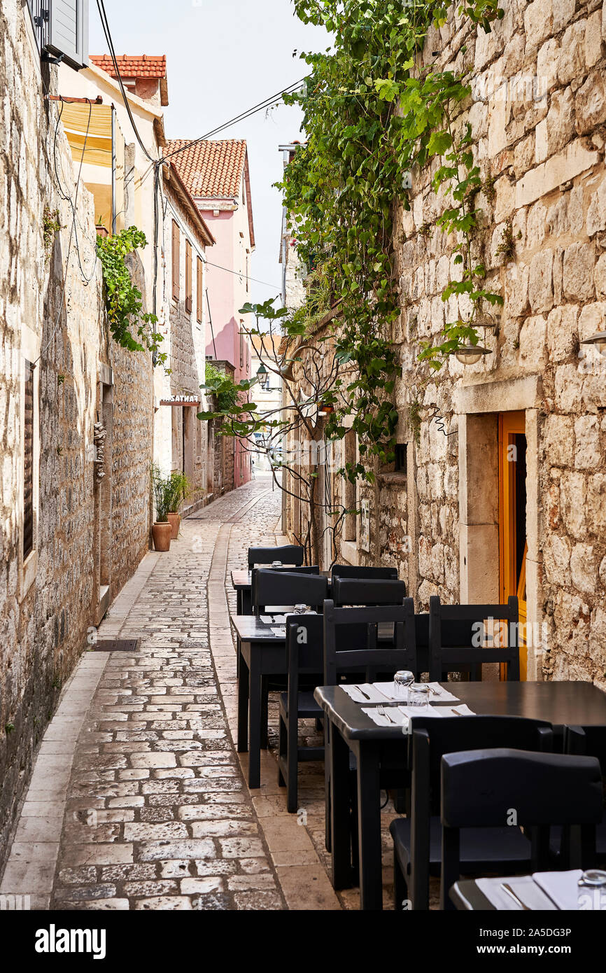 Restaurant tables in narrow street in Stari Grad town, Hvar, Croatia ...