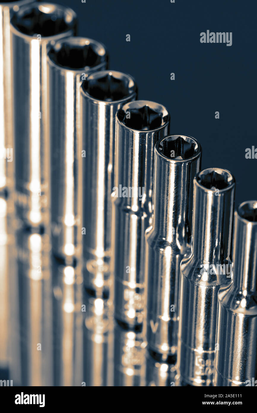 Set of various sized hexagonal chrome sockets in a row reflected on a ...
