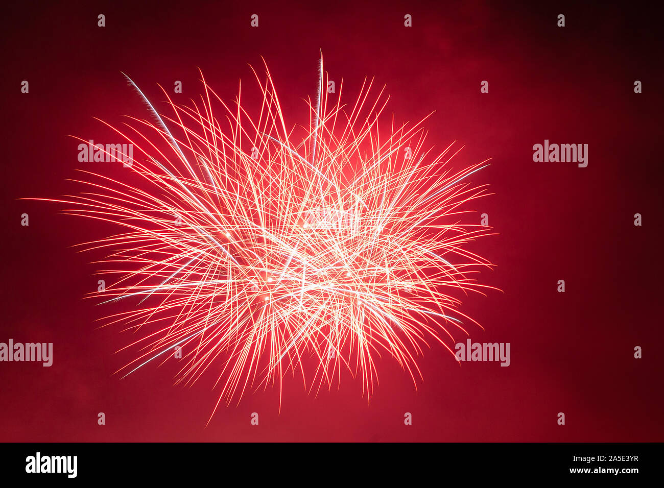 Bright red and white fireworks against the backdrop of the night sky ...