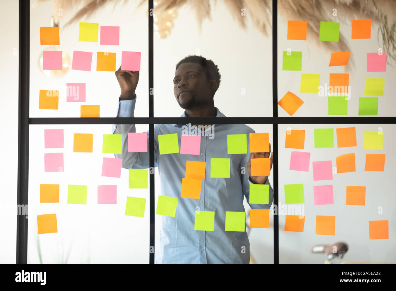 Focused african businessman checking project progress on sticky notes ...